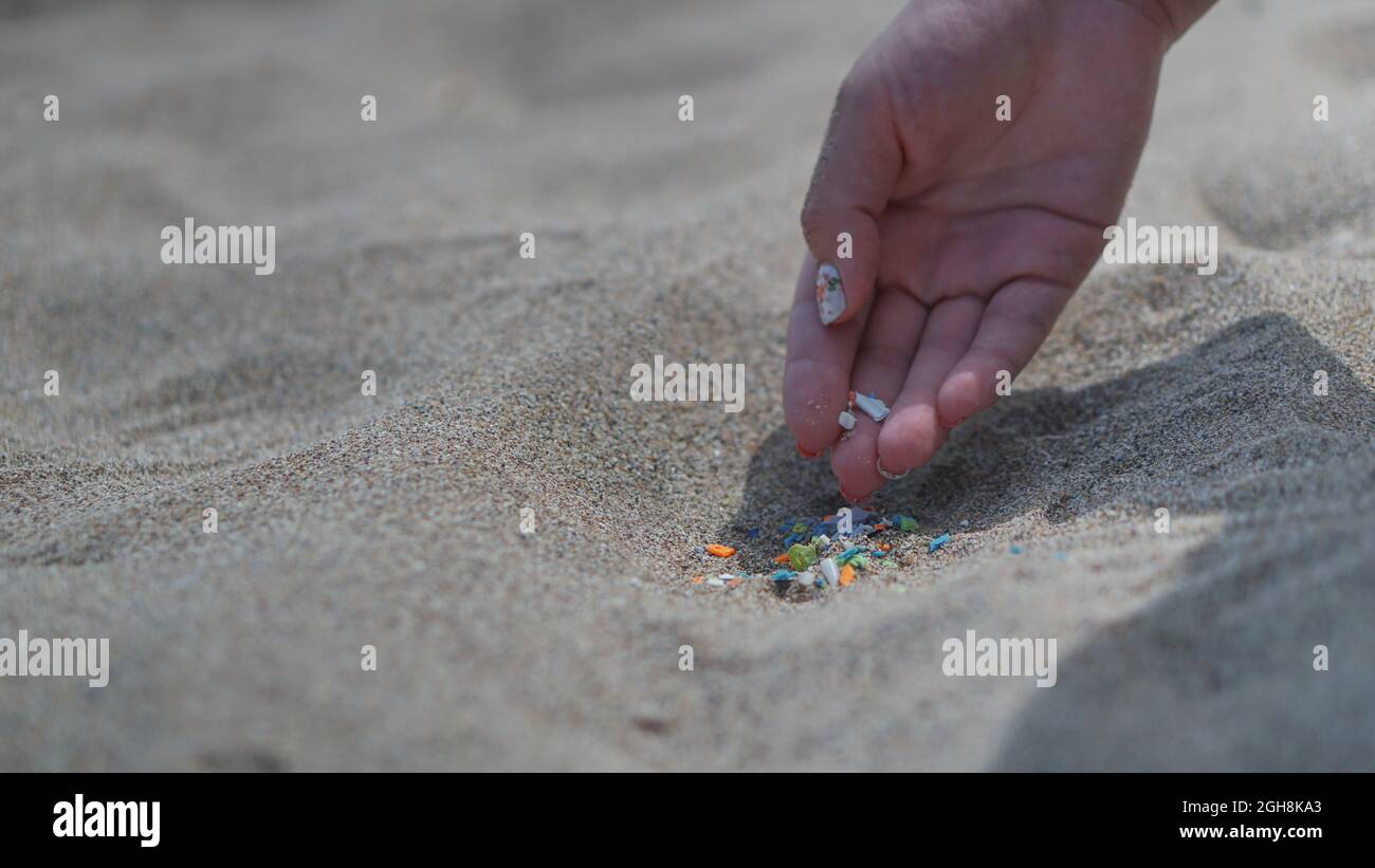 Side view of a hand holding microplastics on the left with copy space ...