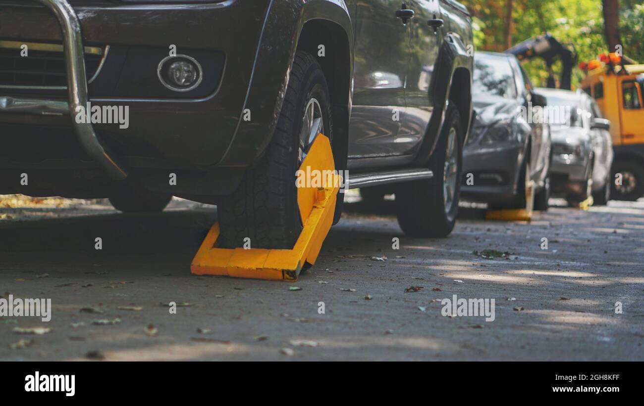 A parked car with a yellow tire lock for the illegal parking violation ...