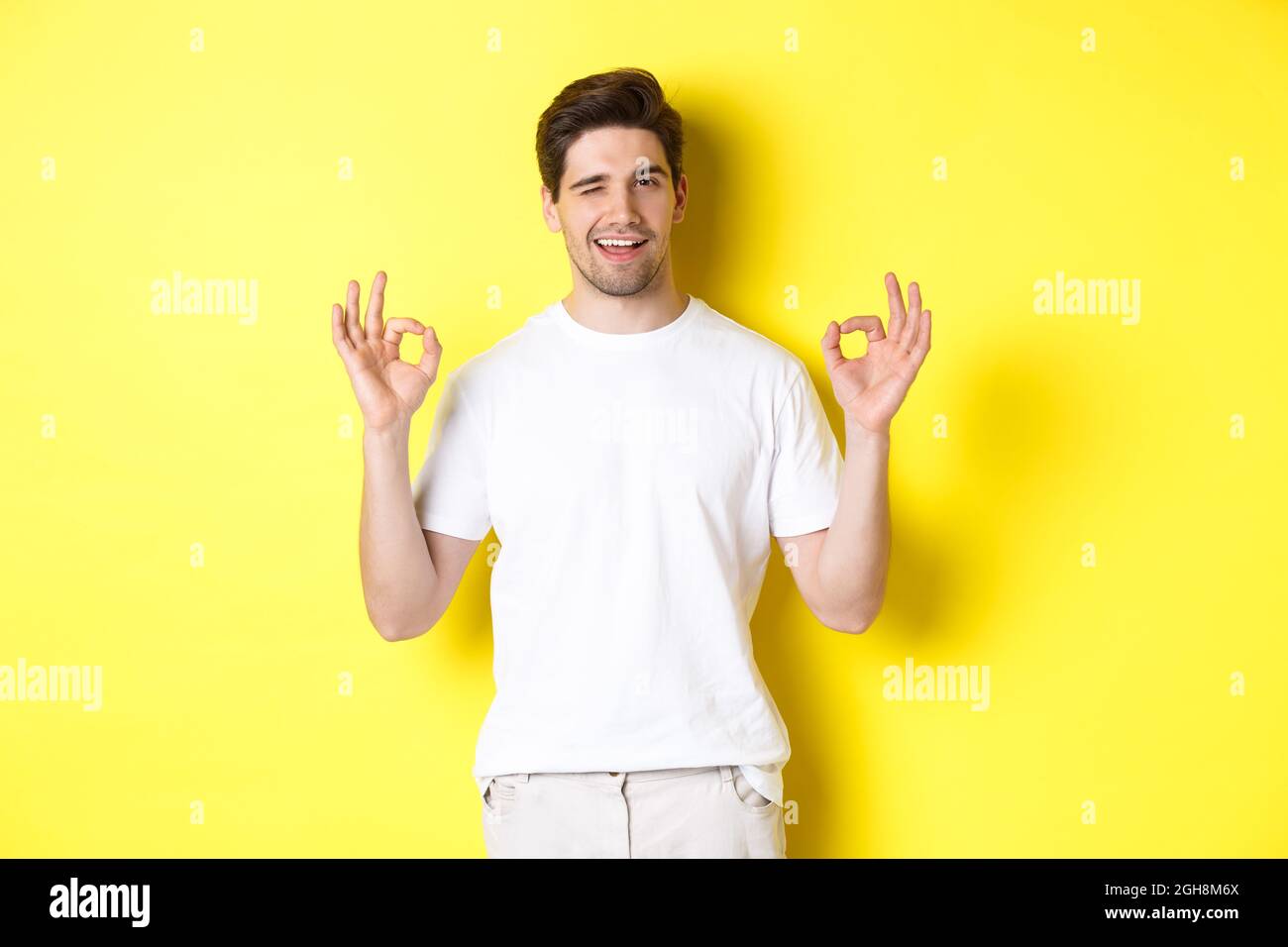 Confident handsome man winking, showing okay signs in approval, like ...