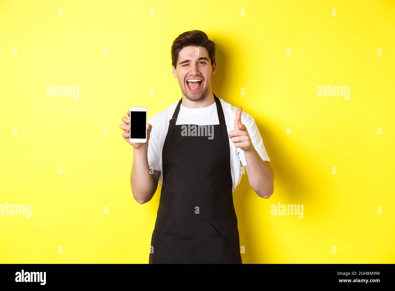 Happy waiter showing mobile screen and thumb up, recommending cafe ...