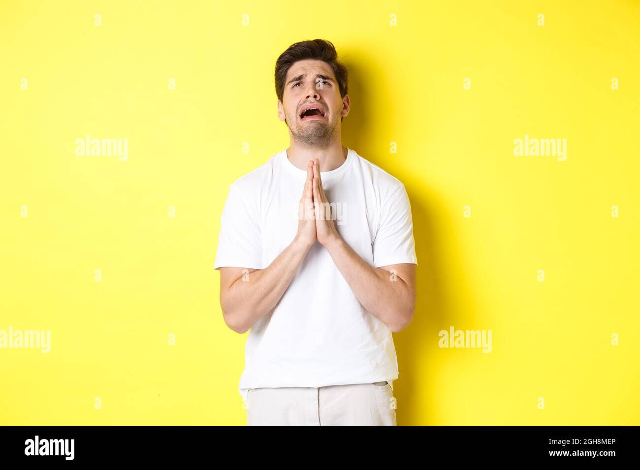 Desperate man pleading God, holding hands in pray and looking up ...