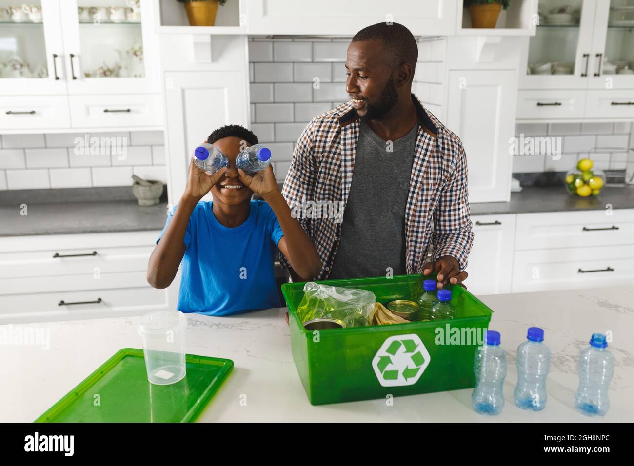 Happy african american son sorting recycling with father in kitchen ...