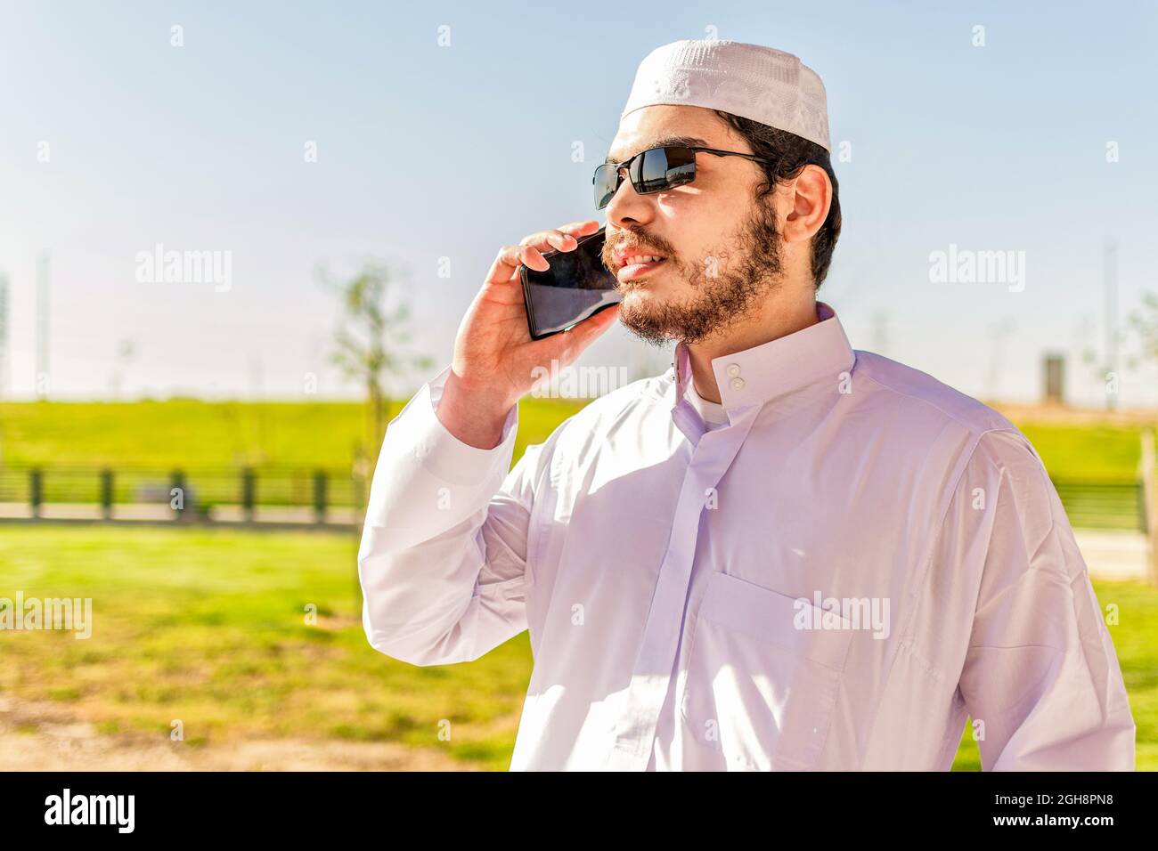 Arab man talking on the phone, in traditional dress, at the park Stock ...