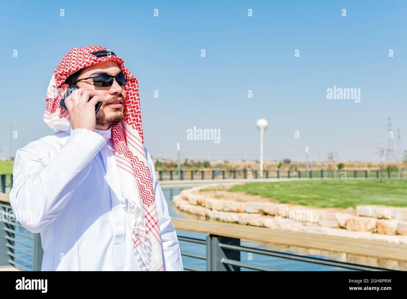 Arab man talking on the phone, in traditional dress, at the park Stock ...