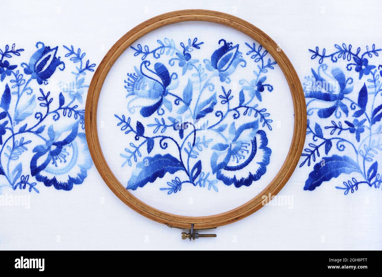 Embroidery hoop with fabric, top view. Blue floral ornament on a white ...