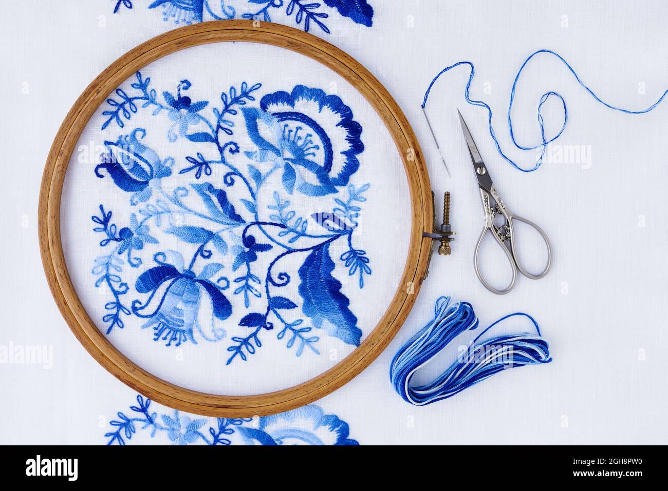 Embroidery hoop with fabric, sewing needle and thread, top view. Blue ...