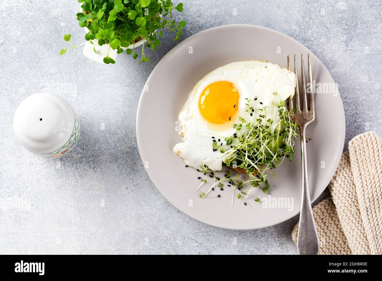 Fried eggs with arugula microgreen in gray ceramic plate on gray ...