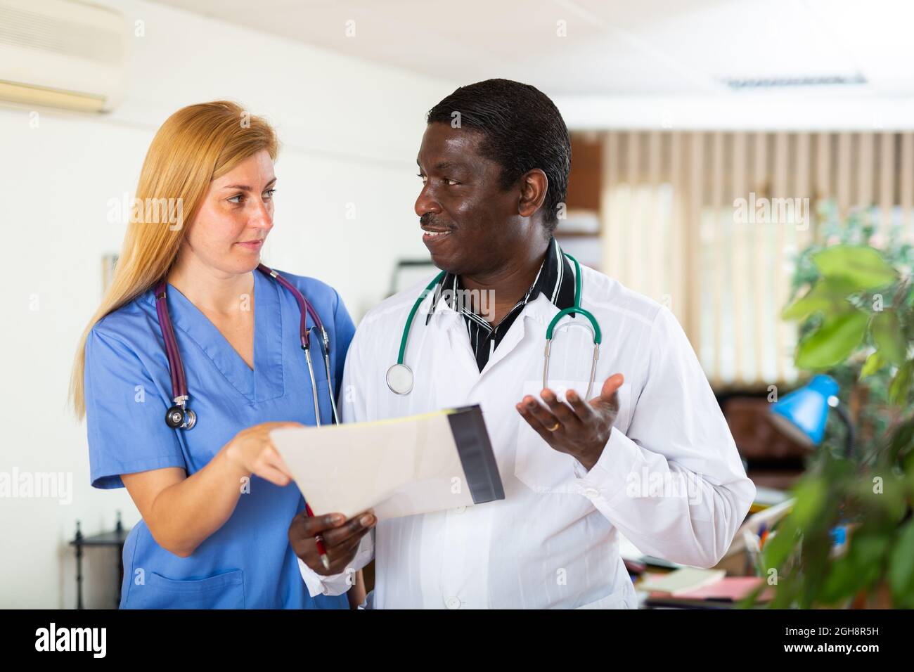 Experienced african american doctor advising his young female colleague ...