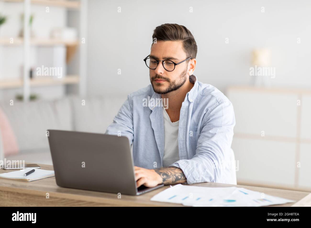 Concentrated self-entrepreneur working with laptop at home office ...