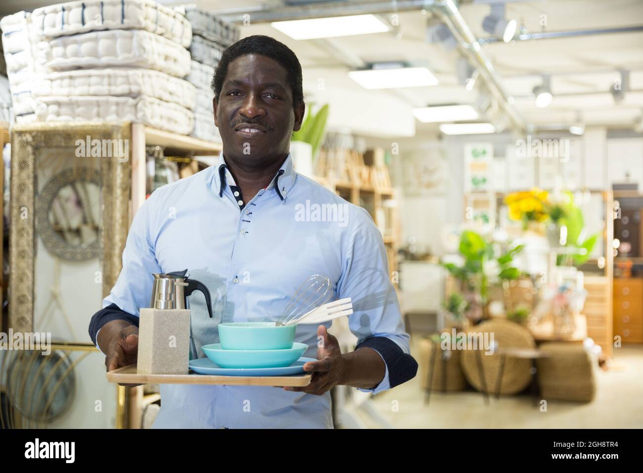Man customer holding purchases and walking in a household goods store ...