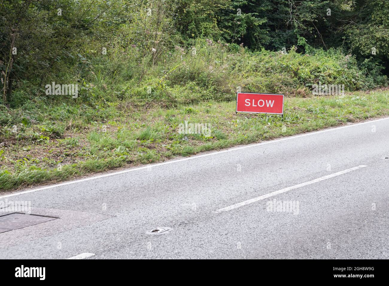 Red SLOW road sign on rural grass verge, warning of roadworks ...