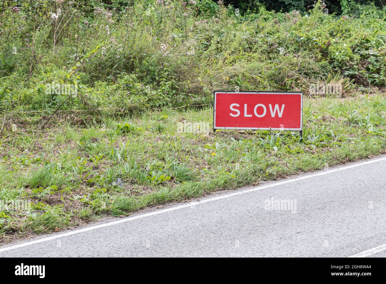 Red SLOW road sign on rural grass verge, warning of roadworks ...