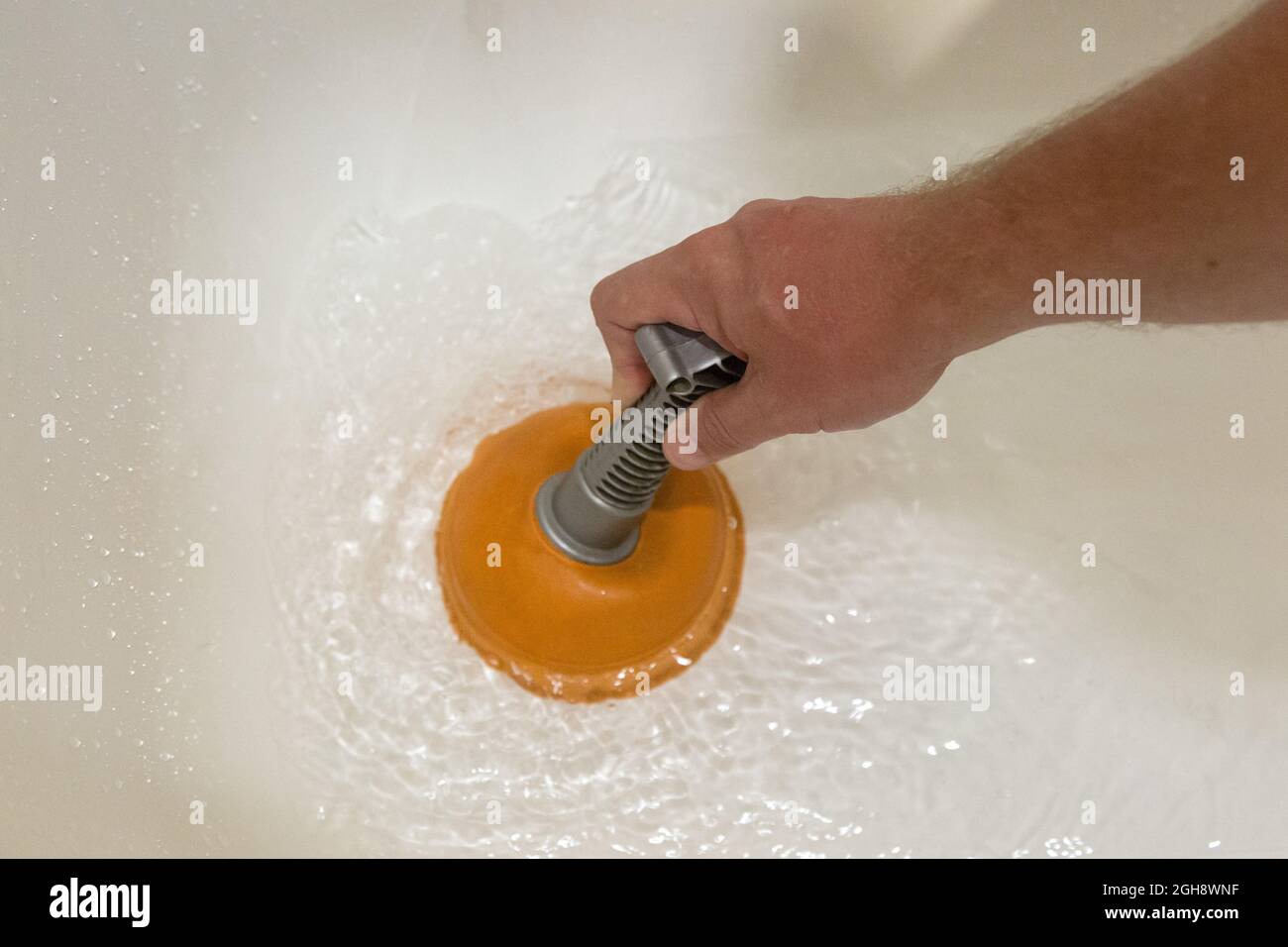 A man's hand with a plunger in bath. Cleaning pipes from blockages ...