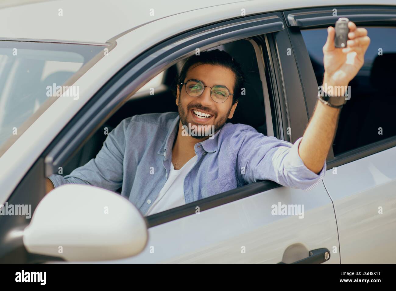 Cheerful indian long-haired guy showing car key and smiling Stock Photo ...