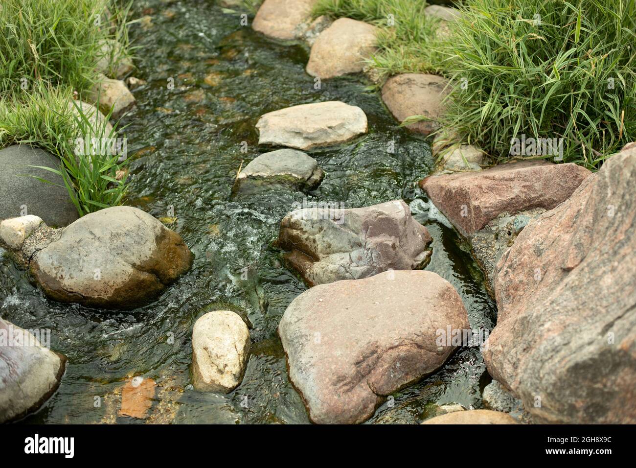 Water runs over the stones. Fresh water stream. Artificial waterfall ...