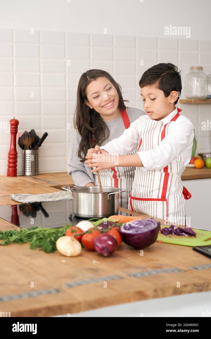 Mother teaches her son how to cook healthy food in the kitchen ...
