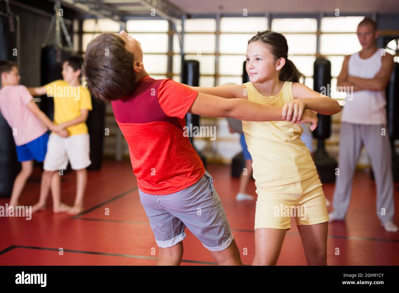 Preteen children practicing in pair self-defence movements with male ...