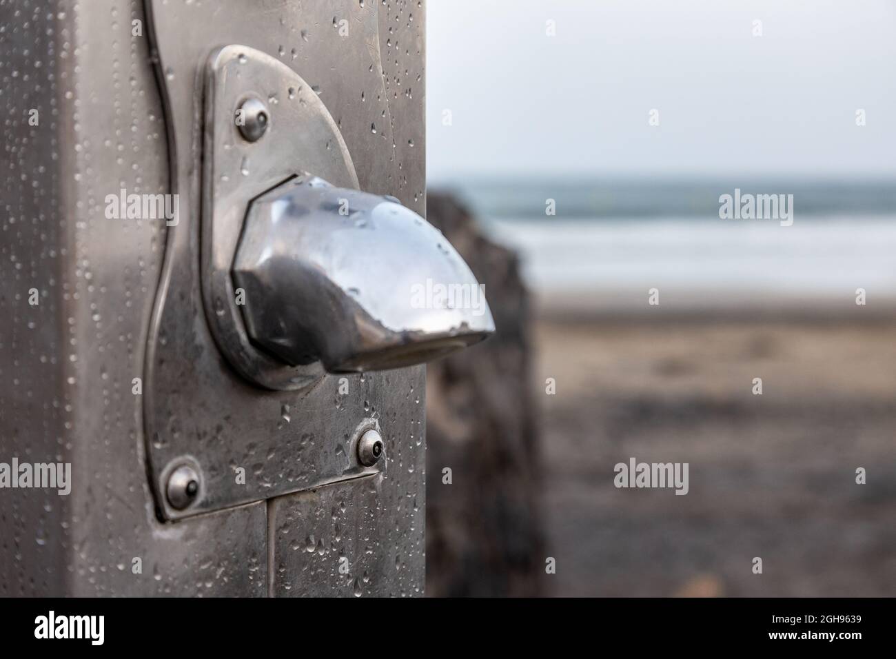 Selective focus shot of an outdoor water tap with ocean in the ...