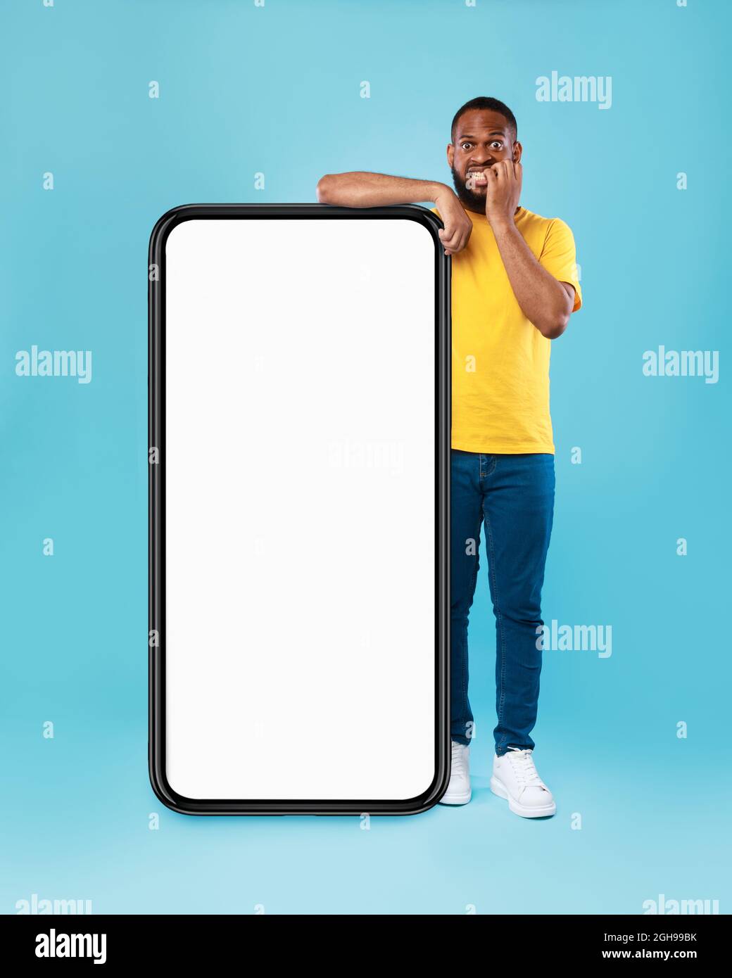 Black guy leaning on giant smartphone with blank screen, biting nails ...