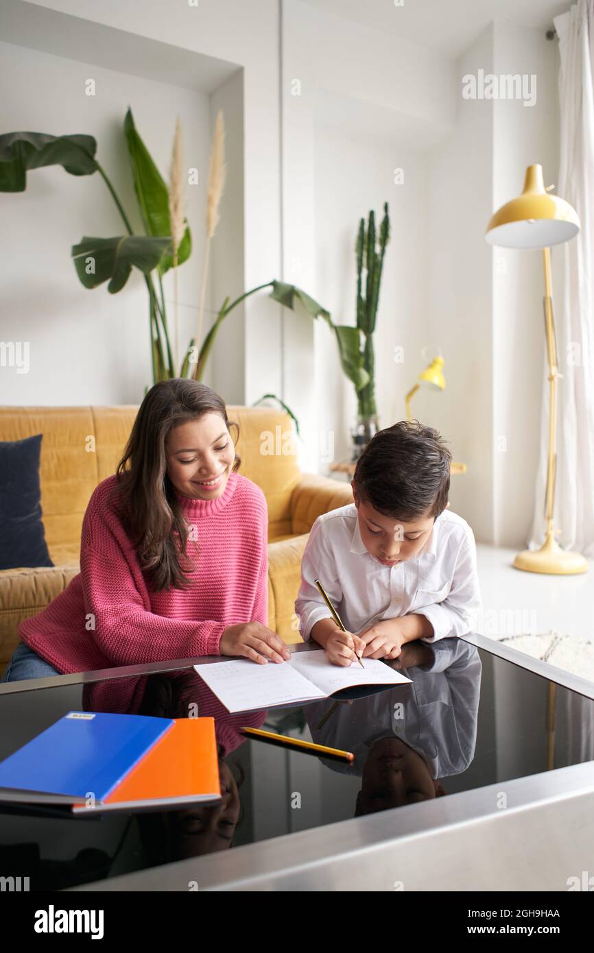 Vertical photo. Mother helping her son with his homework in the living room at home Stock Photo ...