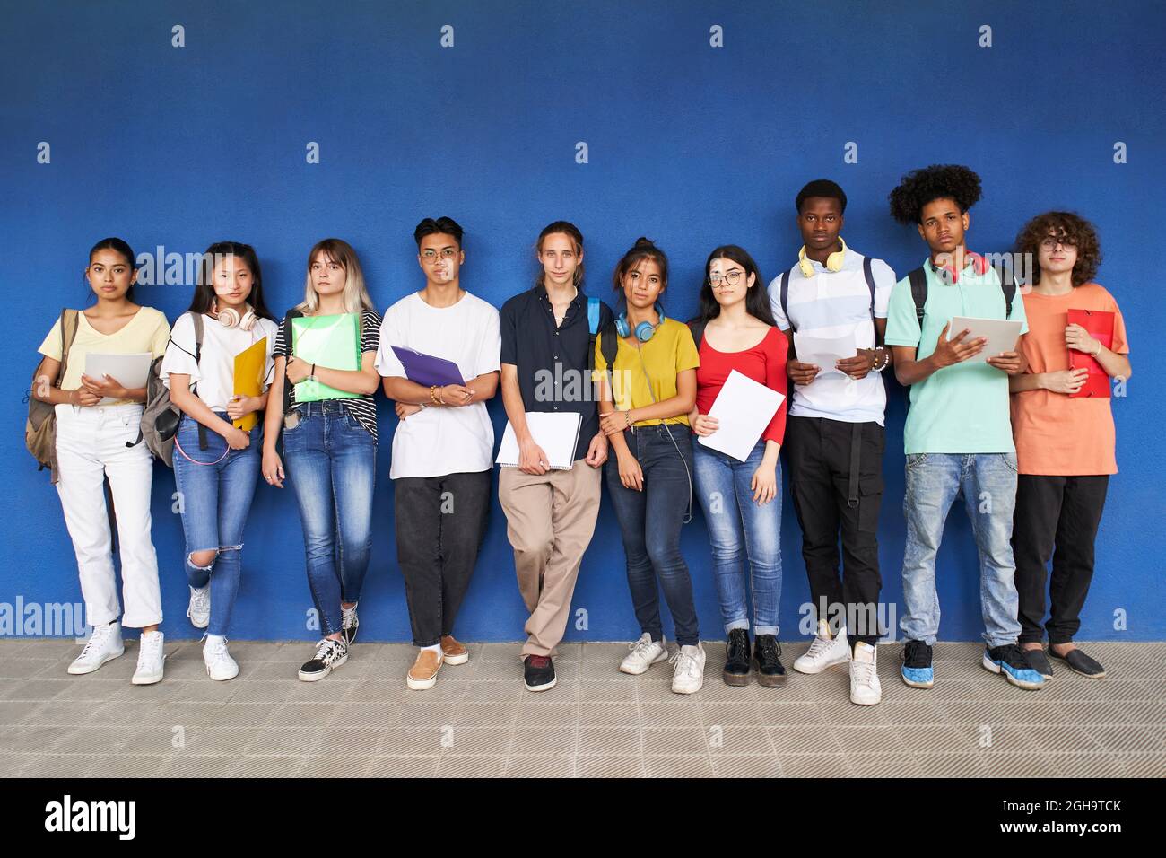 Wide angle of group of students in high school on a blue wall. Young ...