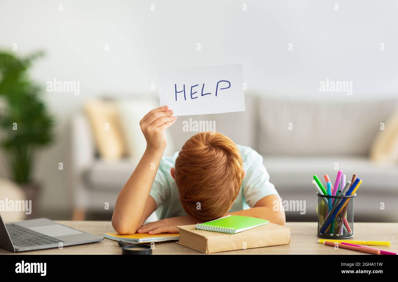 Exhausted schooler doing homework, showing help card Stock Photo - Alamy