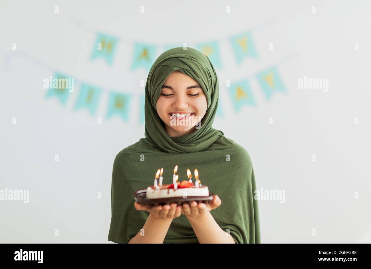 Muslim teen girl in hijab holding birthday cake with burning candles ...