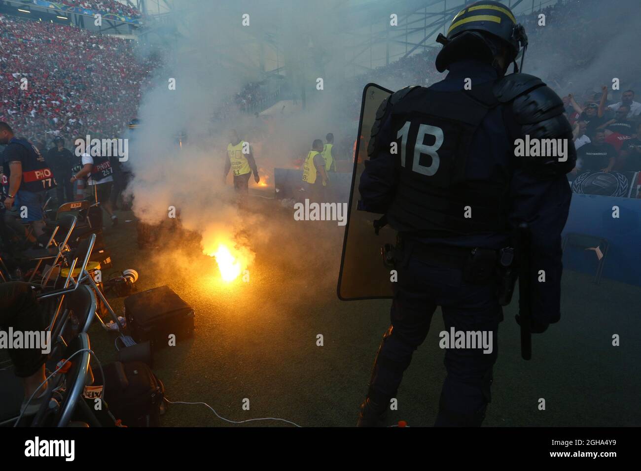A riot police officer stands guard as a flare burns during the UEFA ...