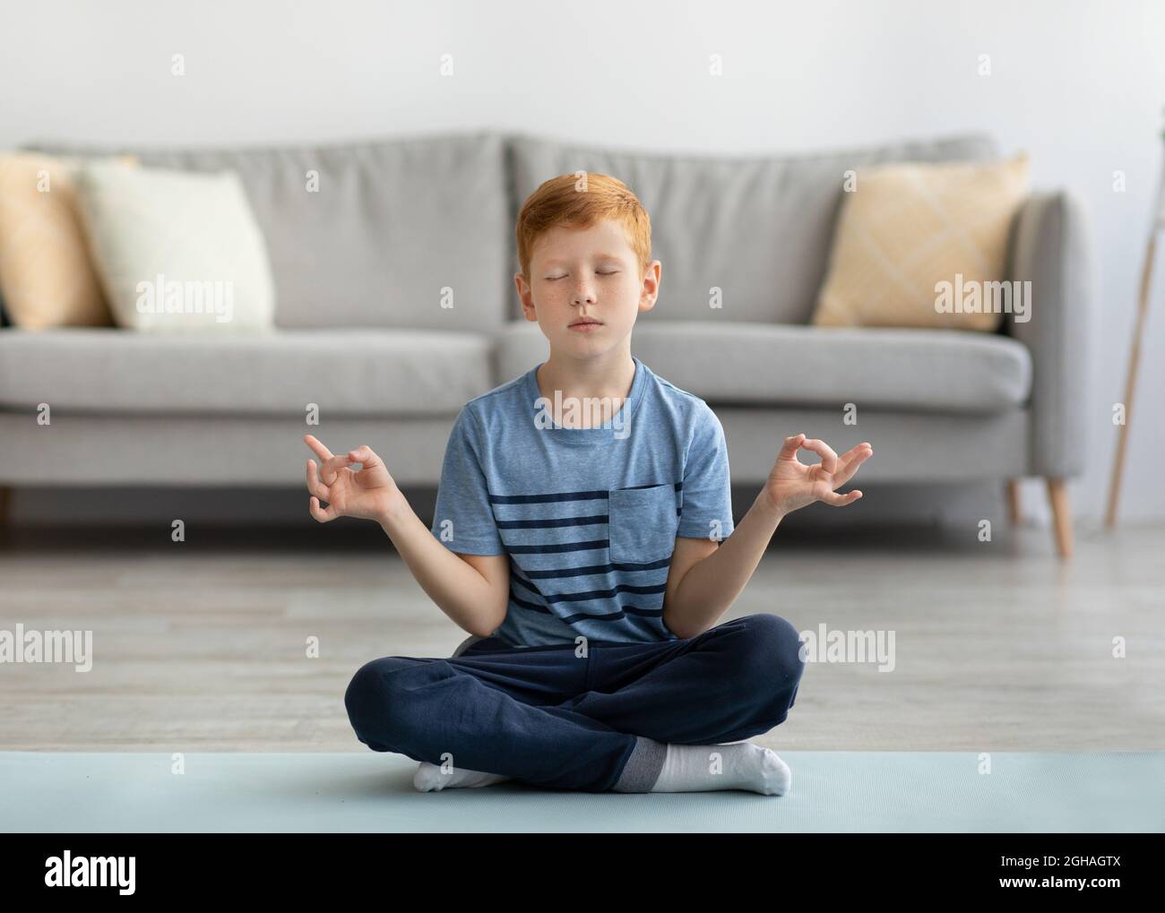 Relaxed boy sitting on fitness mat at home, meditating Stock Photo - Alamy