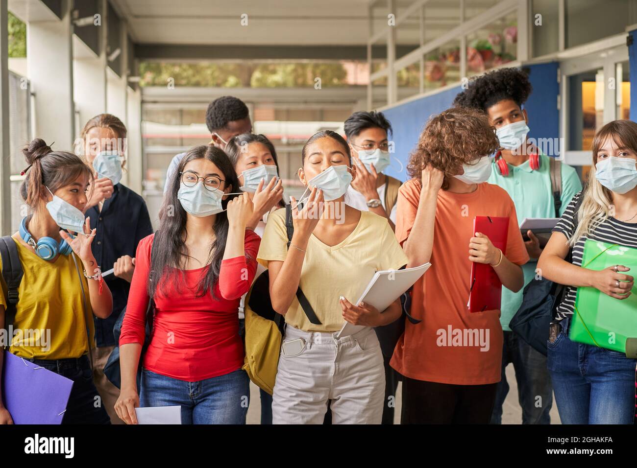 Group of students putting on or taking off their face masks. Young ...