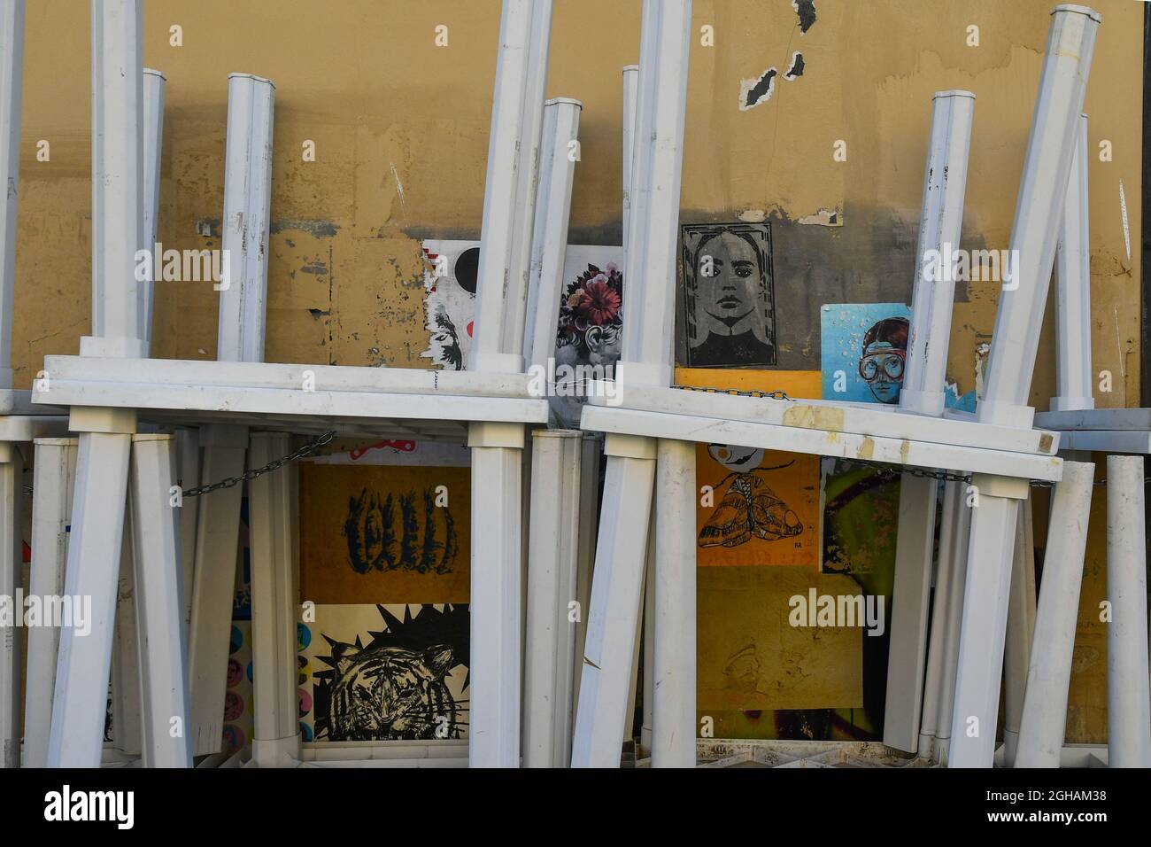 Tables stacked against a graffiti wall with artworks by different ...