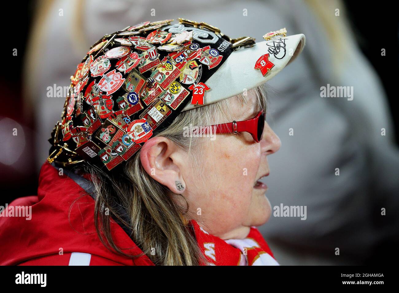 A liverpool fan wears a hat covered in badges hi-res stock photography ...