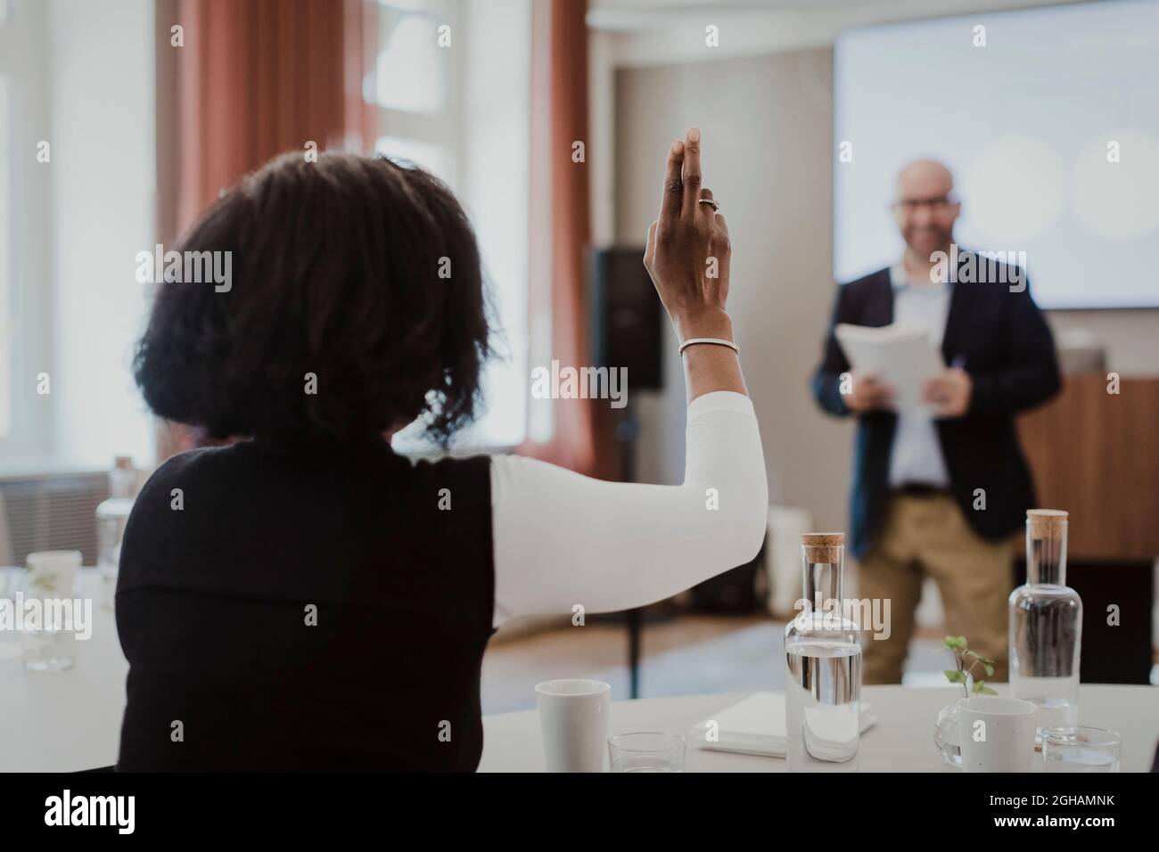 Rear view of businesswoman asking question while male colleague giving ...