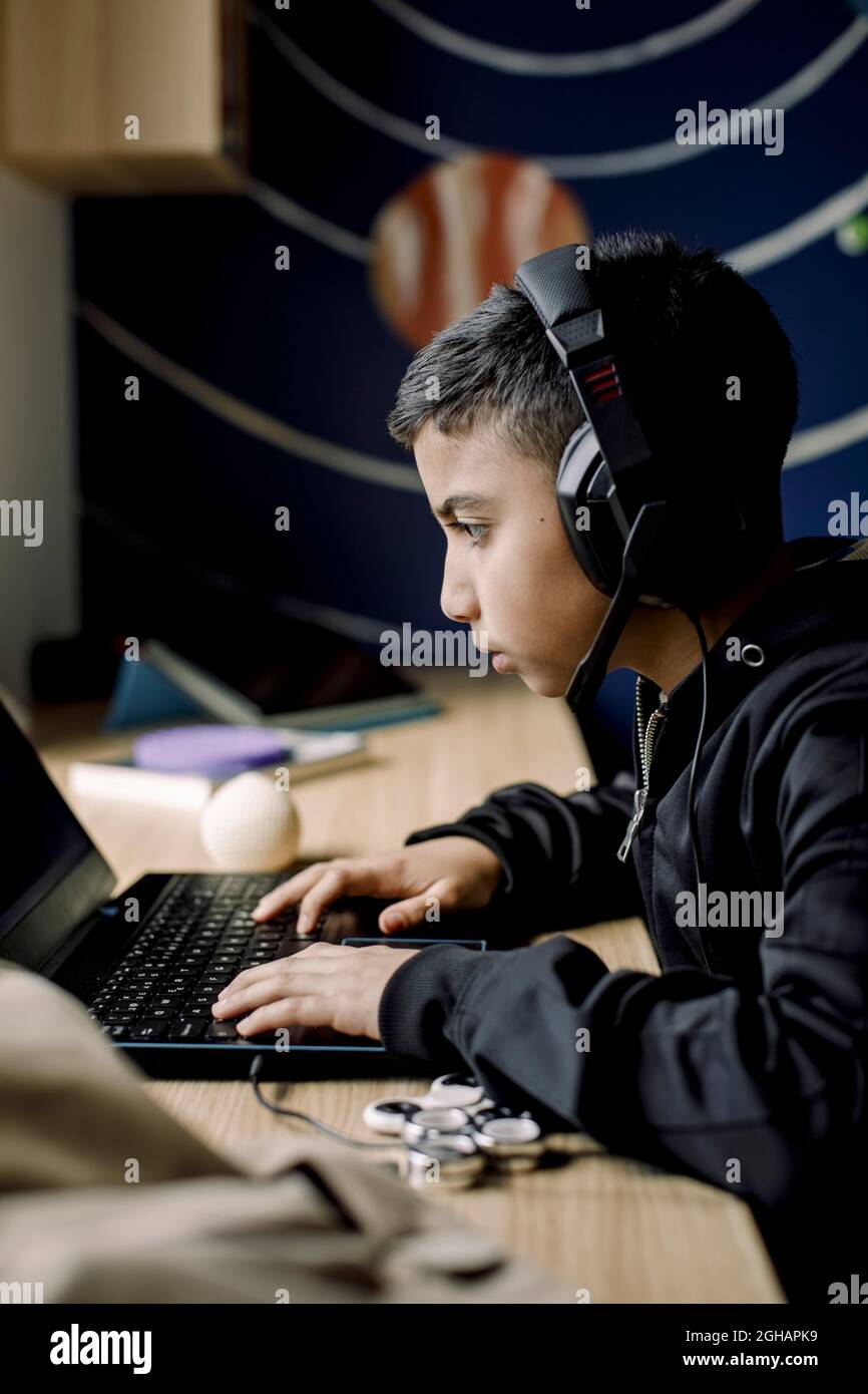 Pre-adolescent boy playing game on laptop in bedroom Stock Photo - Alamy