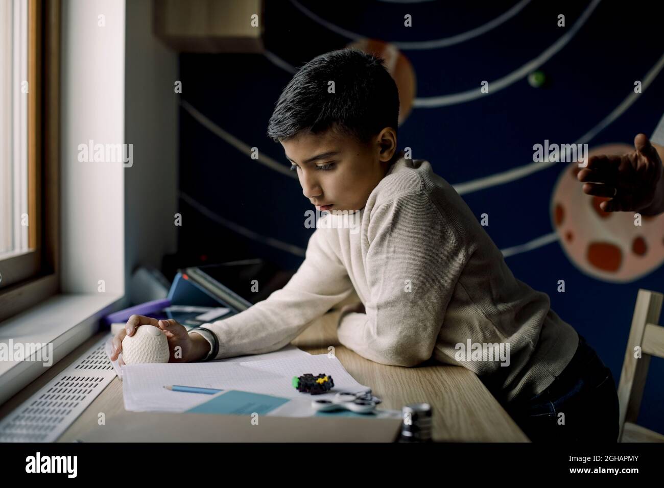 Autistic boy holding stress ball while reading book at home Stock Photo ...