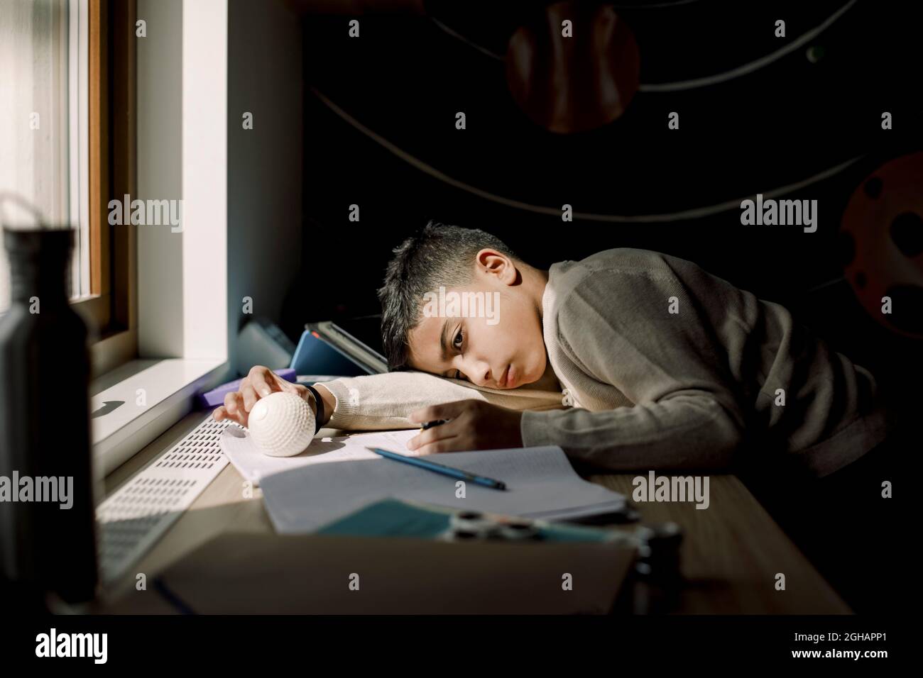 Tired pre-adolescent boy resting head on table in bedroom Stock Photo ...