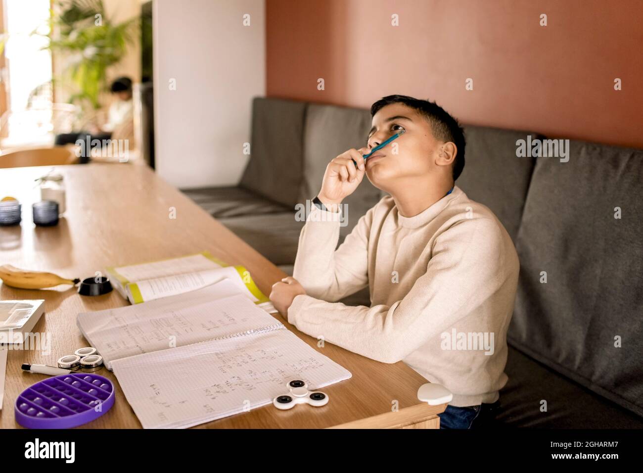 Boy contemplating while sitting on sofa in living room Stock Photo - Alamy