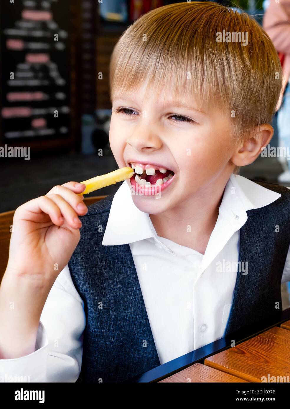Happy Kid eats Fries Potatoes in a Fast Food Restaurant Stock Photo - Alamy