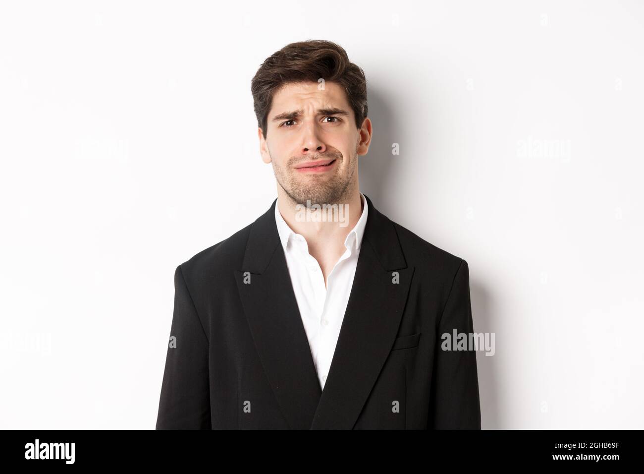 Close-up of confused handsome man in suit, grimacing and looking ...