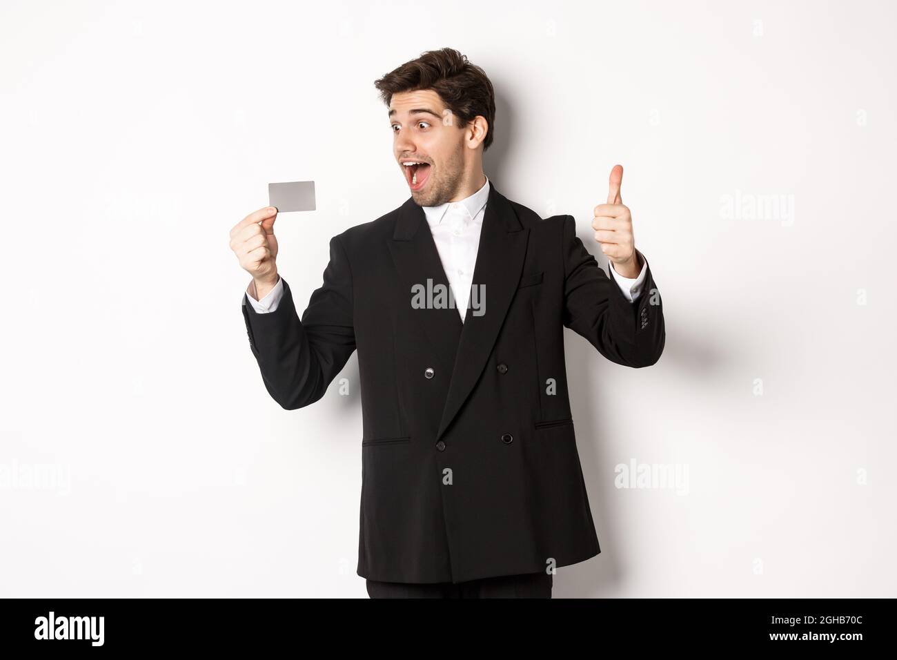 Image of excited handsome businessman, showing credit card and thumb-up ...