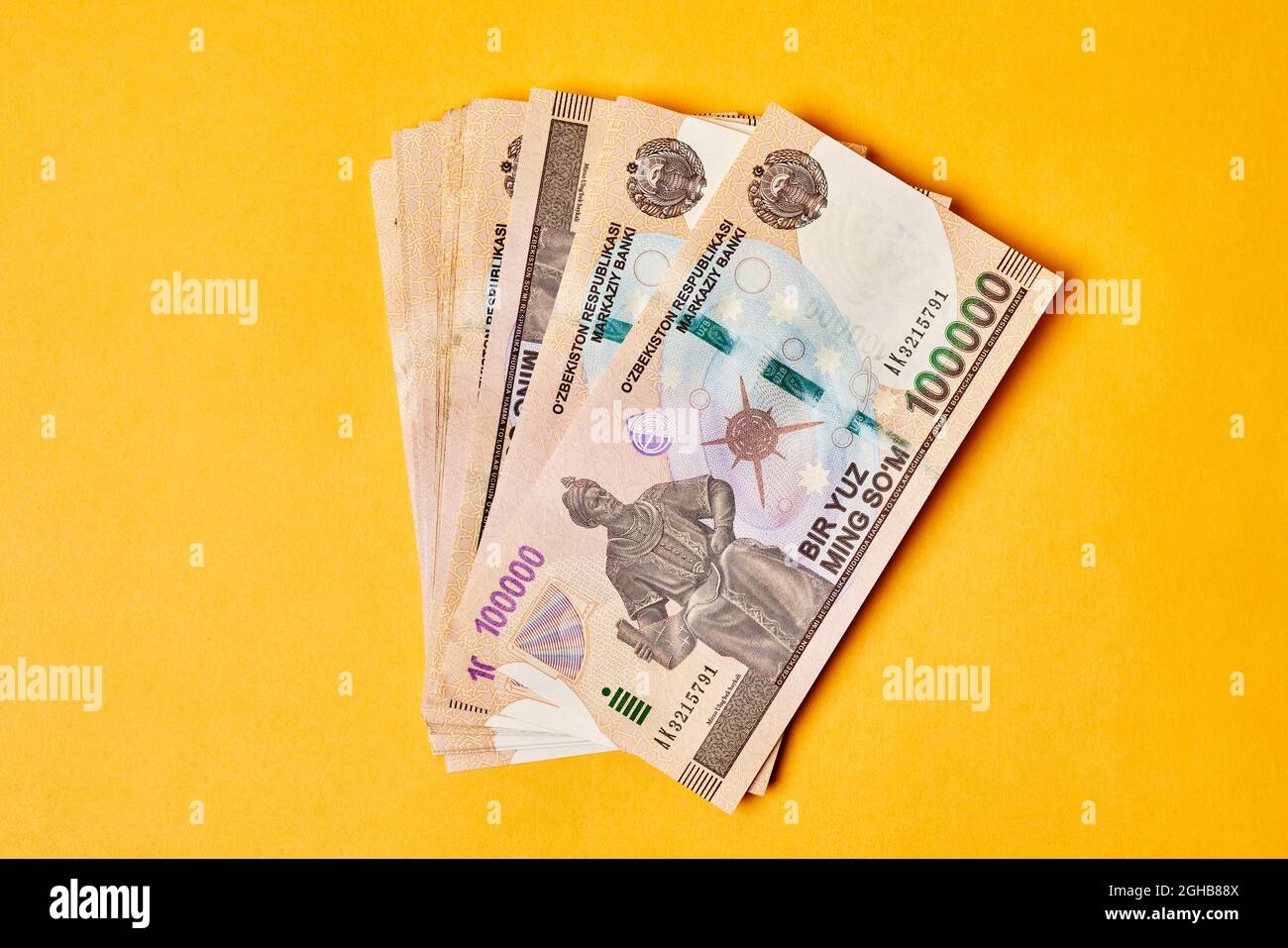 Pile of Uzbek sums on yellow. Uzbek currency money bill. A stack of one ...