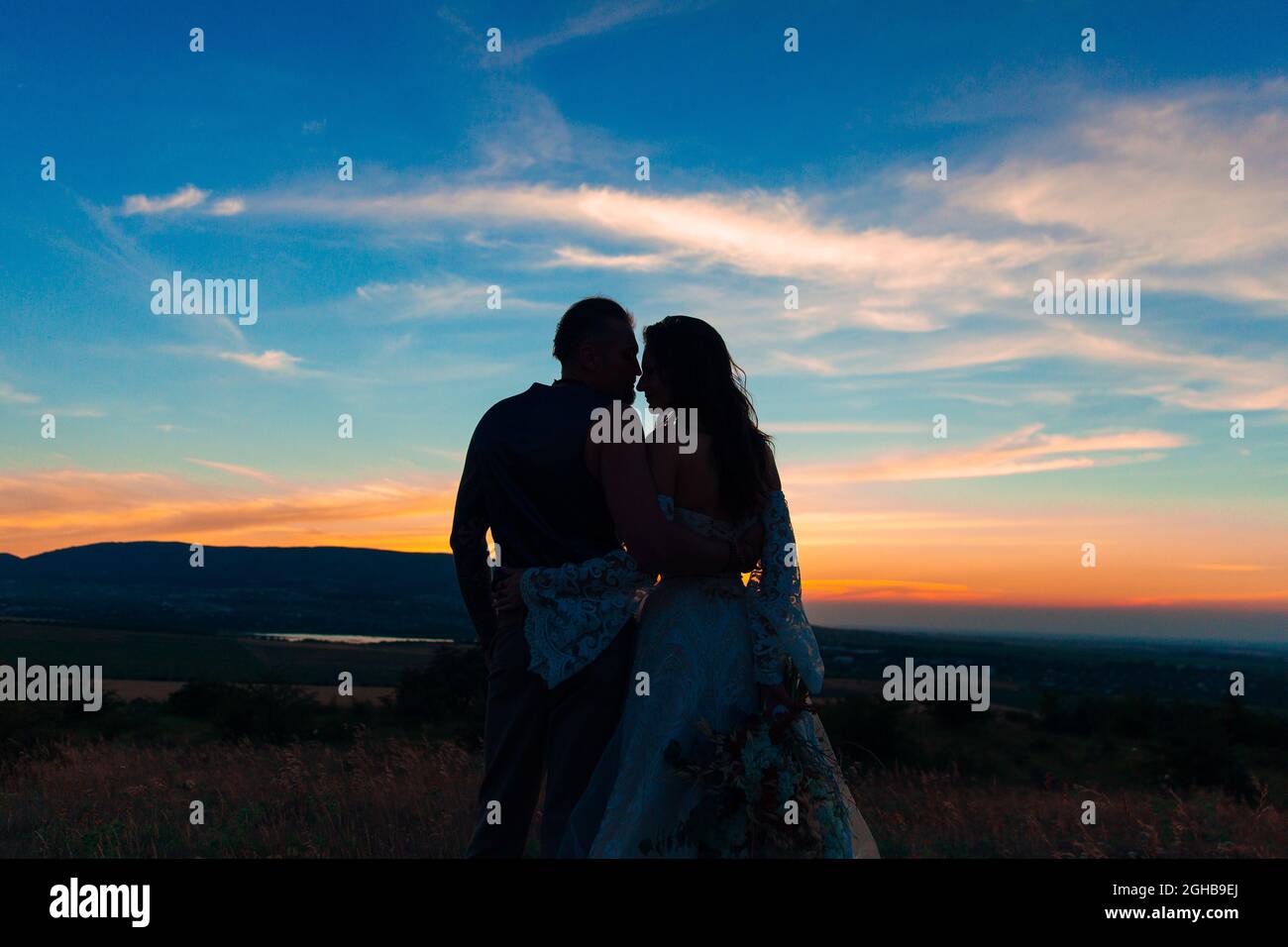 Silhouette of a couple hugging and kissing at sunset against the ...