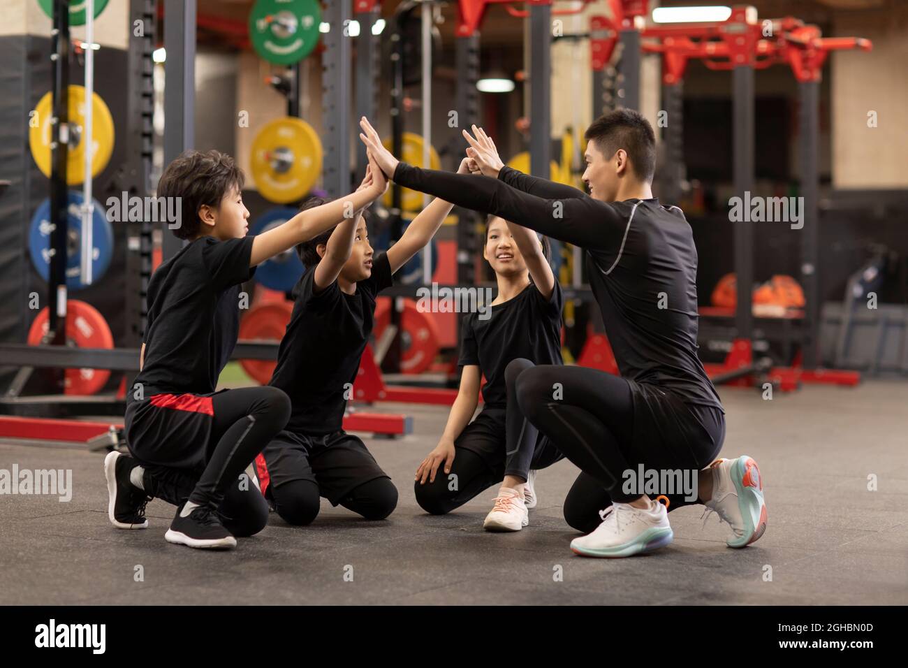 Active children and coach high fiving in gym Stock Photo - Alamy