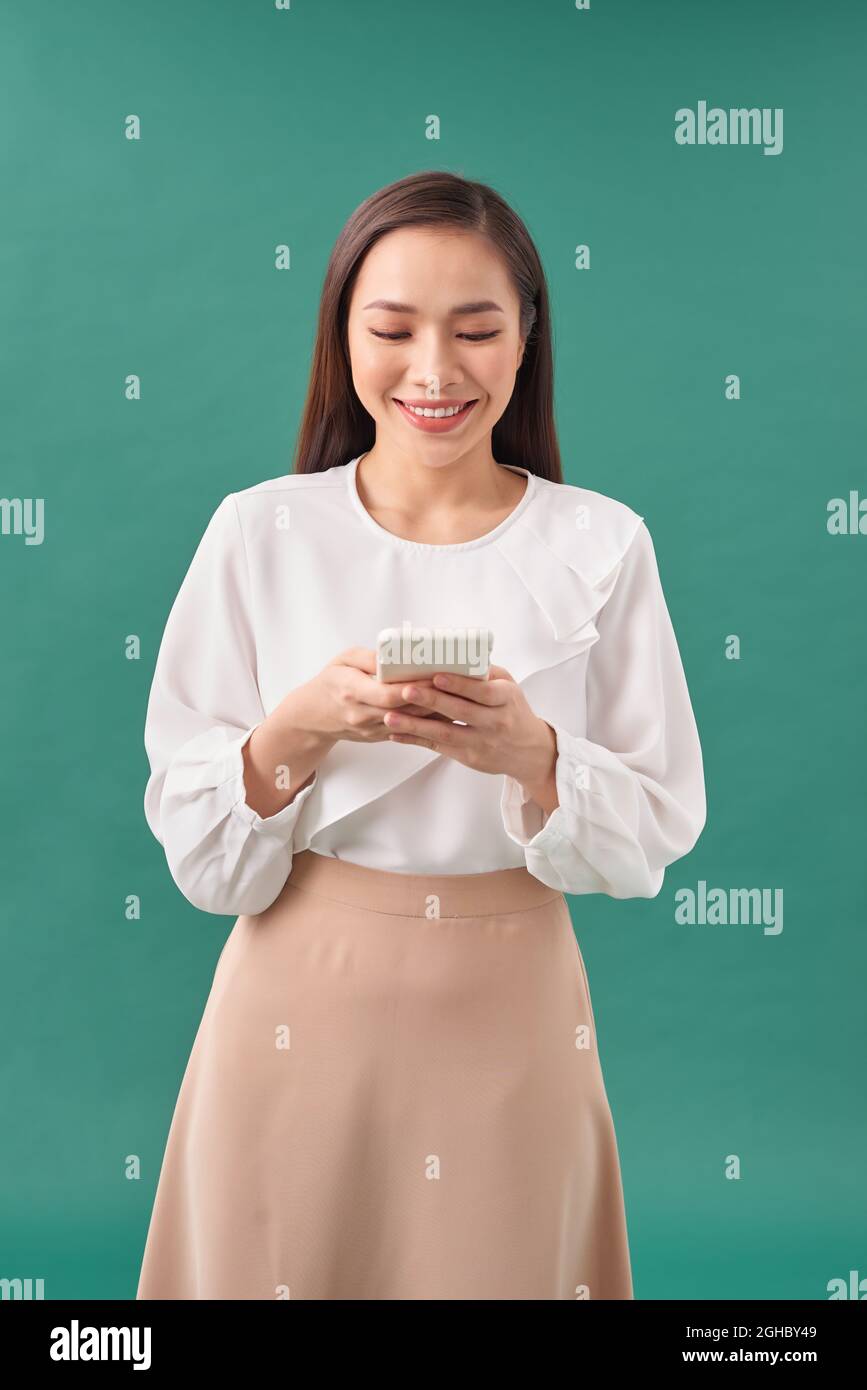 Smiling young woman girl using mobile phone typing sms message on ...