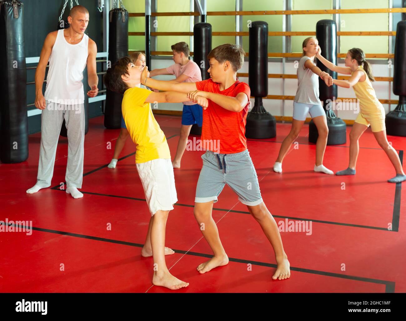 Positive kids in pair exercising self-defense movements during group ...