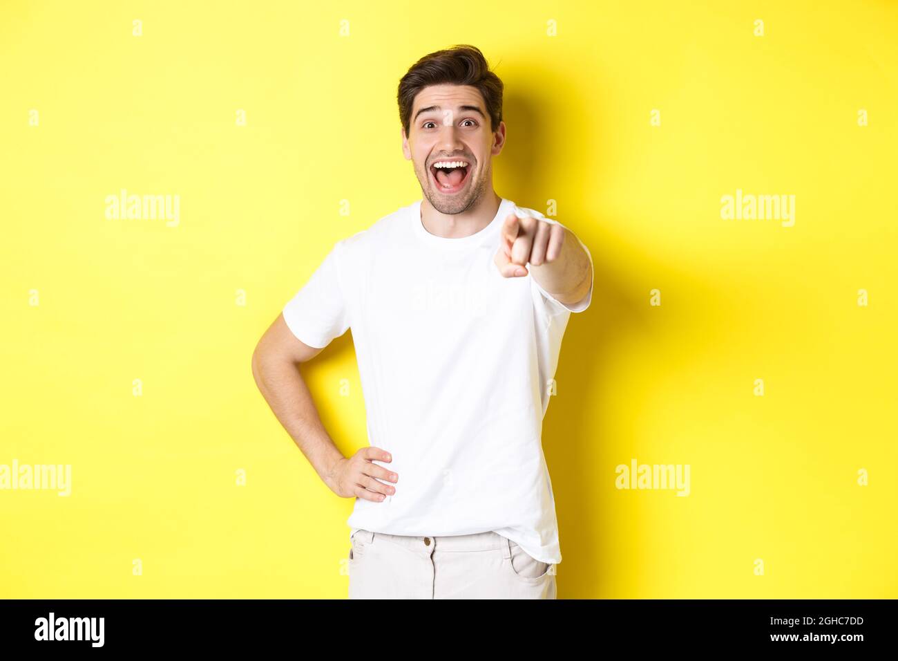 Happy guy pointing finger at camera and laughing, check out something ...