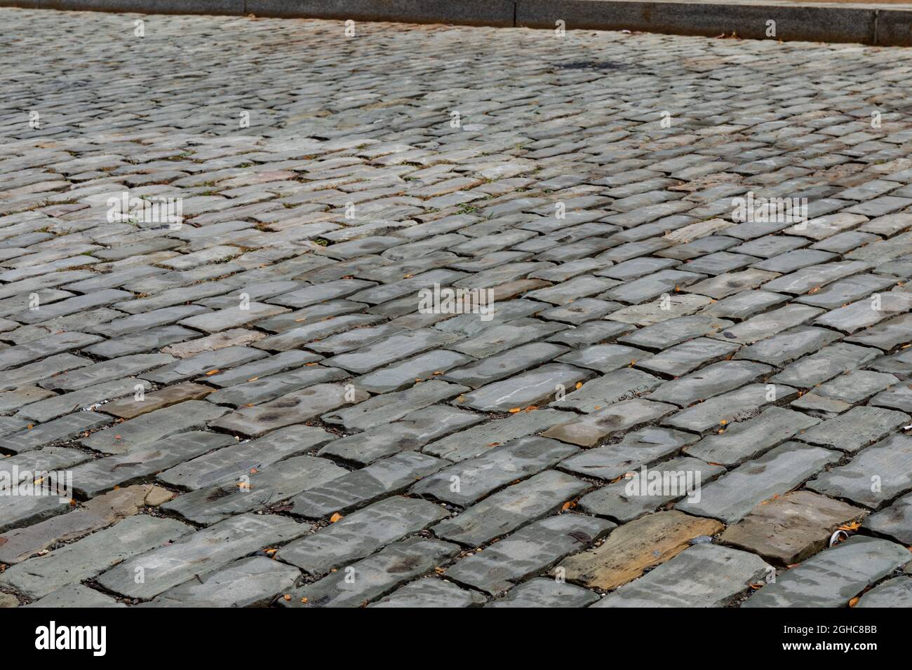 Low view of a gray stone block street seen from an oblique angle ...