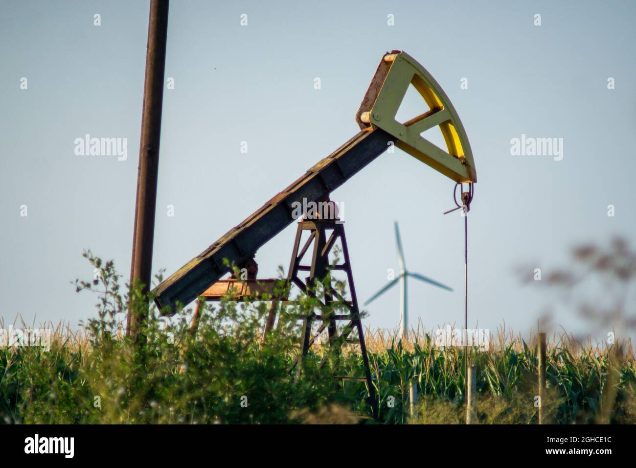 OIL PUMP VERSUS WIND TURBINE IN THE BACKGROUND. CONCEPT: GREEN ENERGY ...