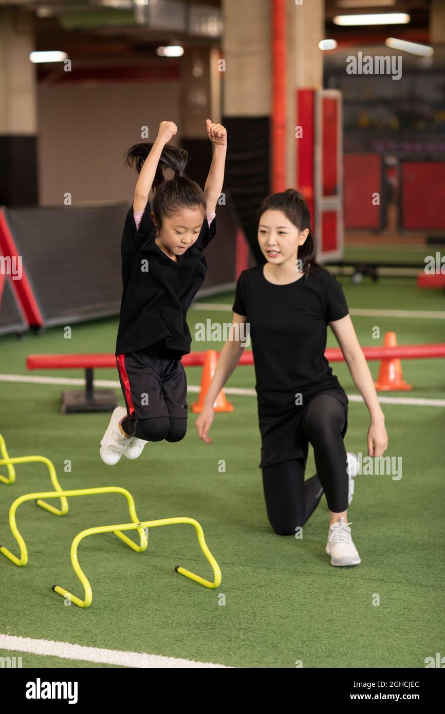 Cute girl having exercise class with coach in gym Stock Photo - Alamy
