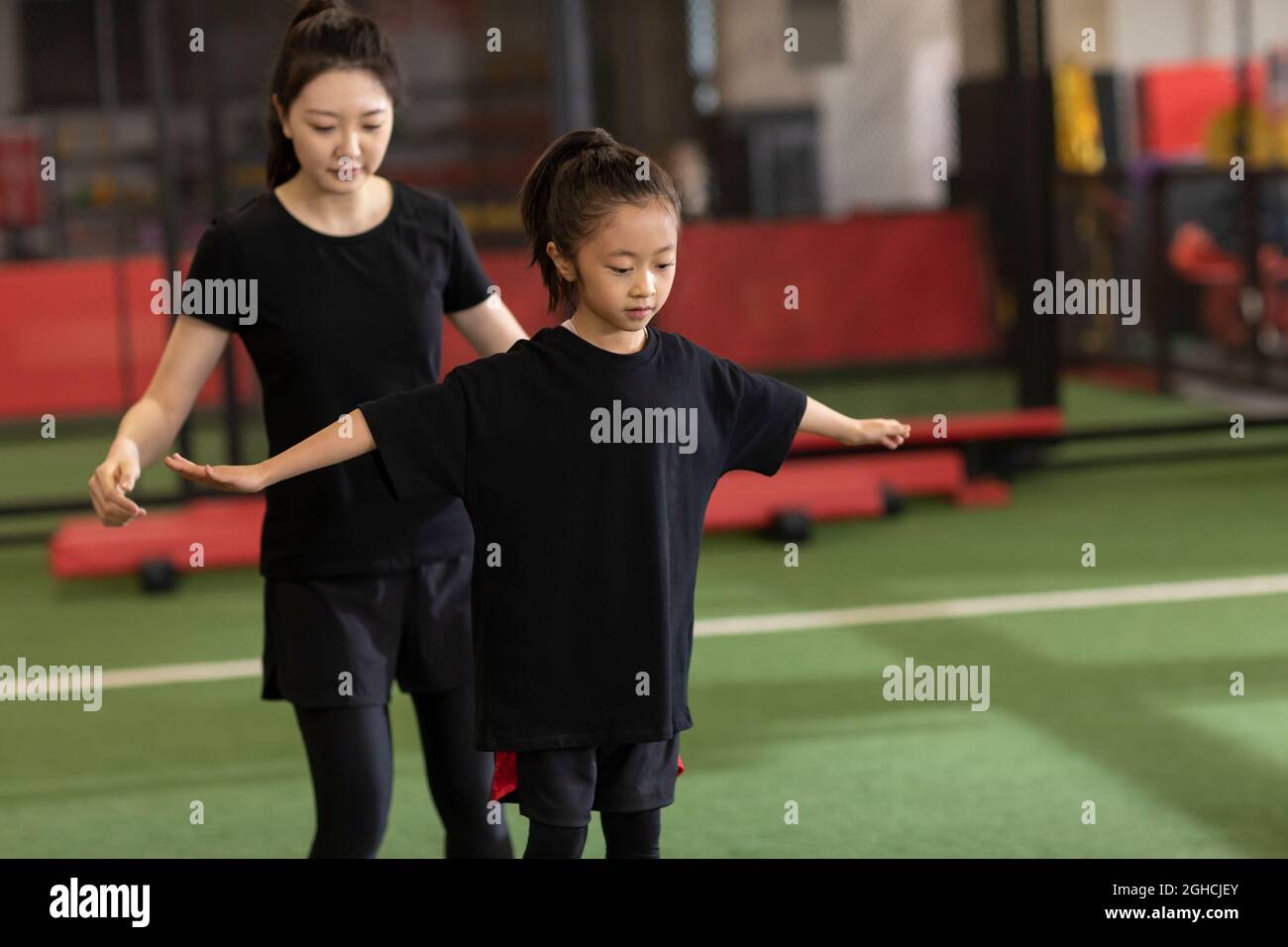 Cute girl having exercise class with coach in gym Stock Photo - Alamy